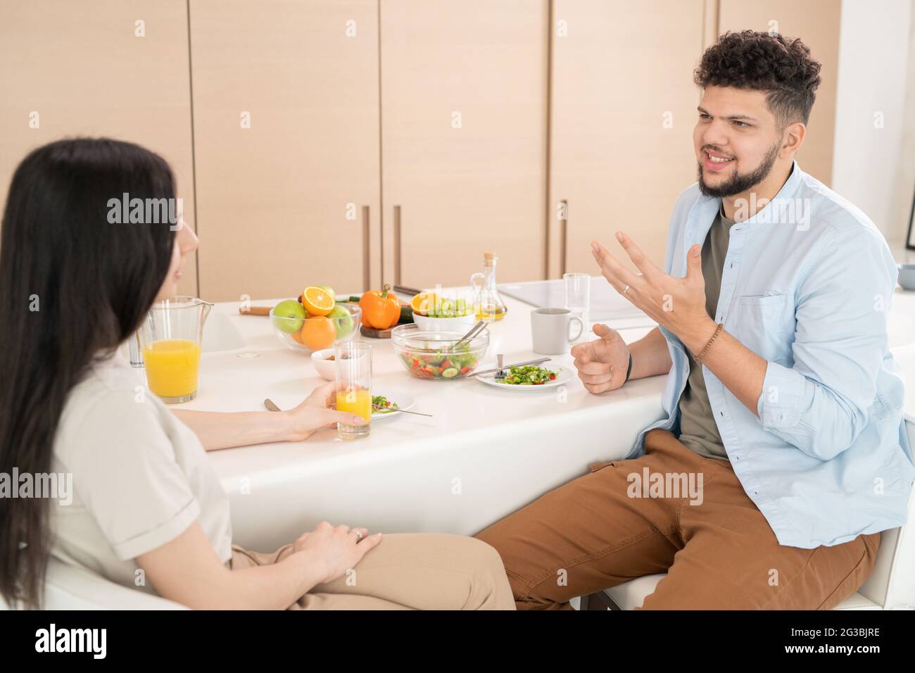 Young couple talking by breakfast while sitting by kitchen table Stock ...