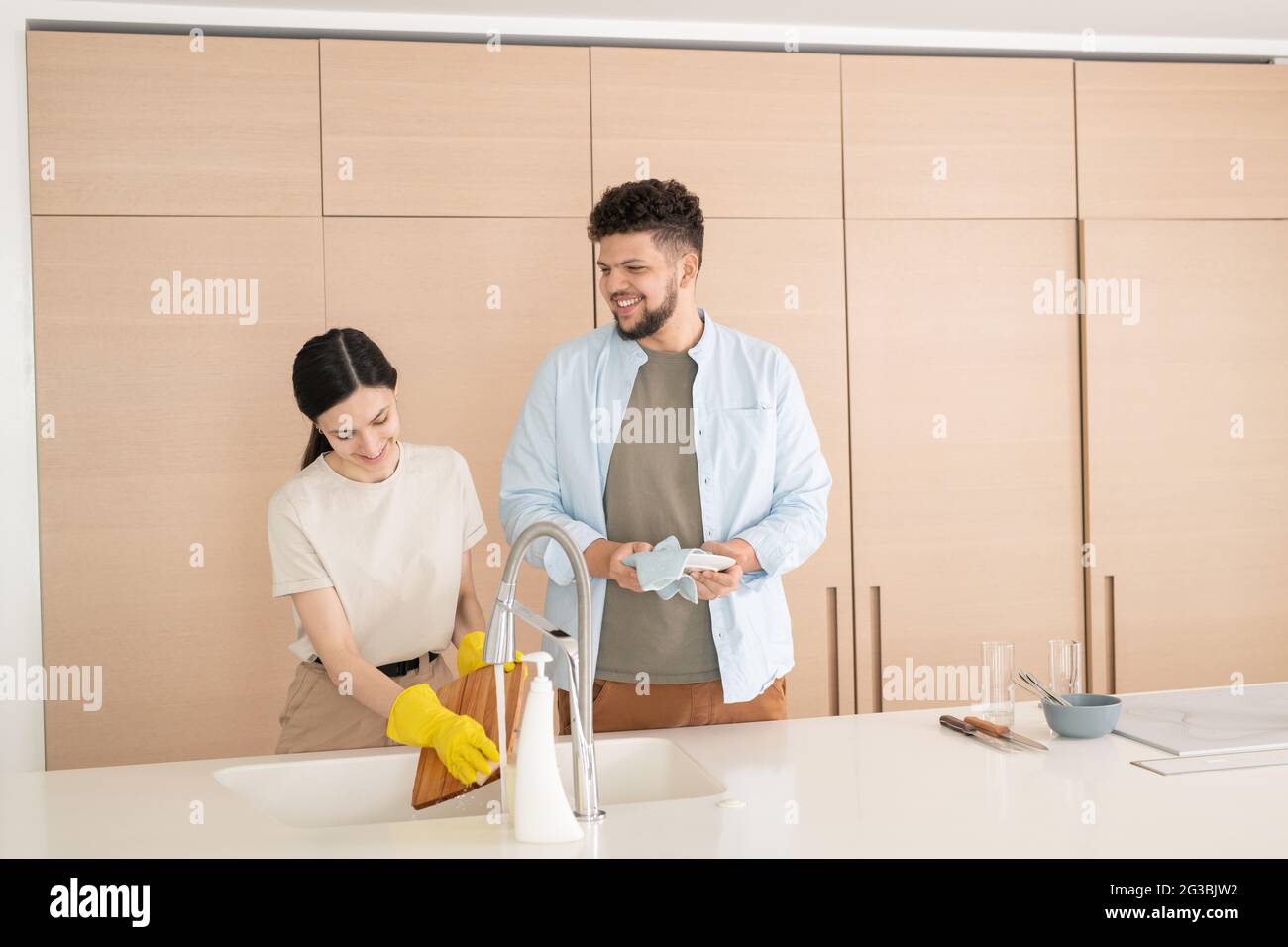 Young man wiping clean plates washed by his wife in the kitchen Stock ...