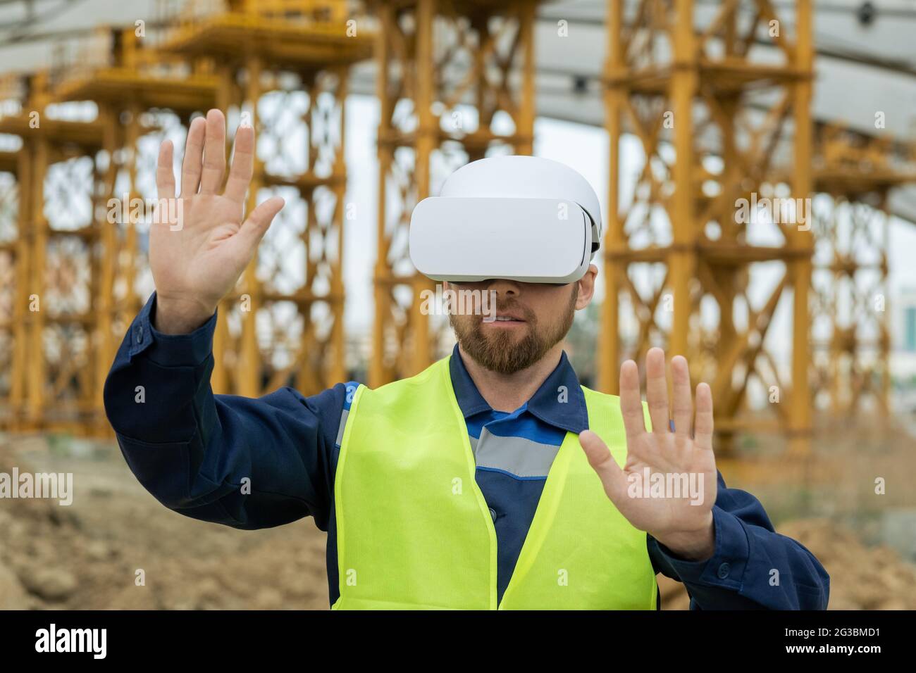 Contemporary builder in vr headset touching virtual display while ...