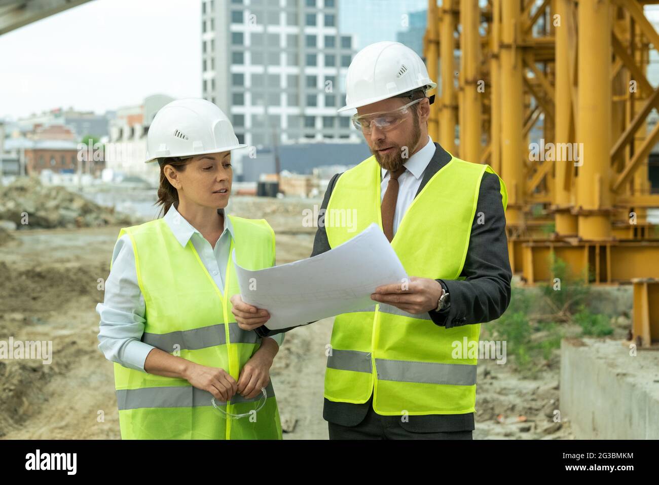 Young female engineer listening to colleague explaining sketch on ...