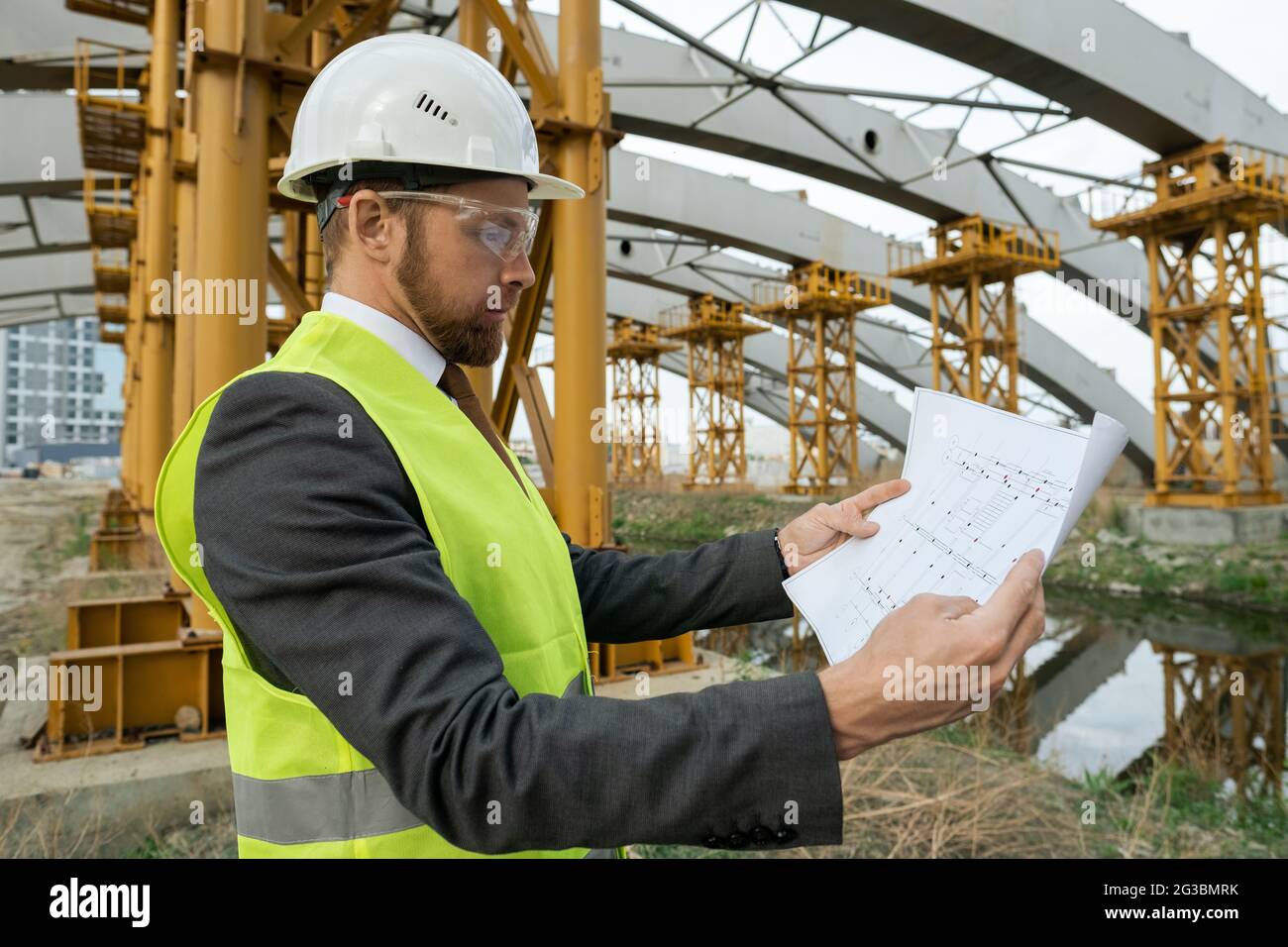 Young serious builder looking at sketch on paper while working Stock ...