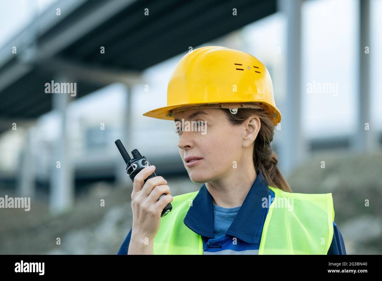Female inspector or engineer using walkie-talkie while working on ...