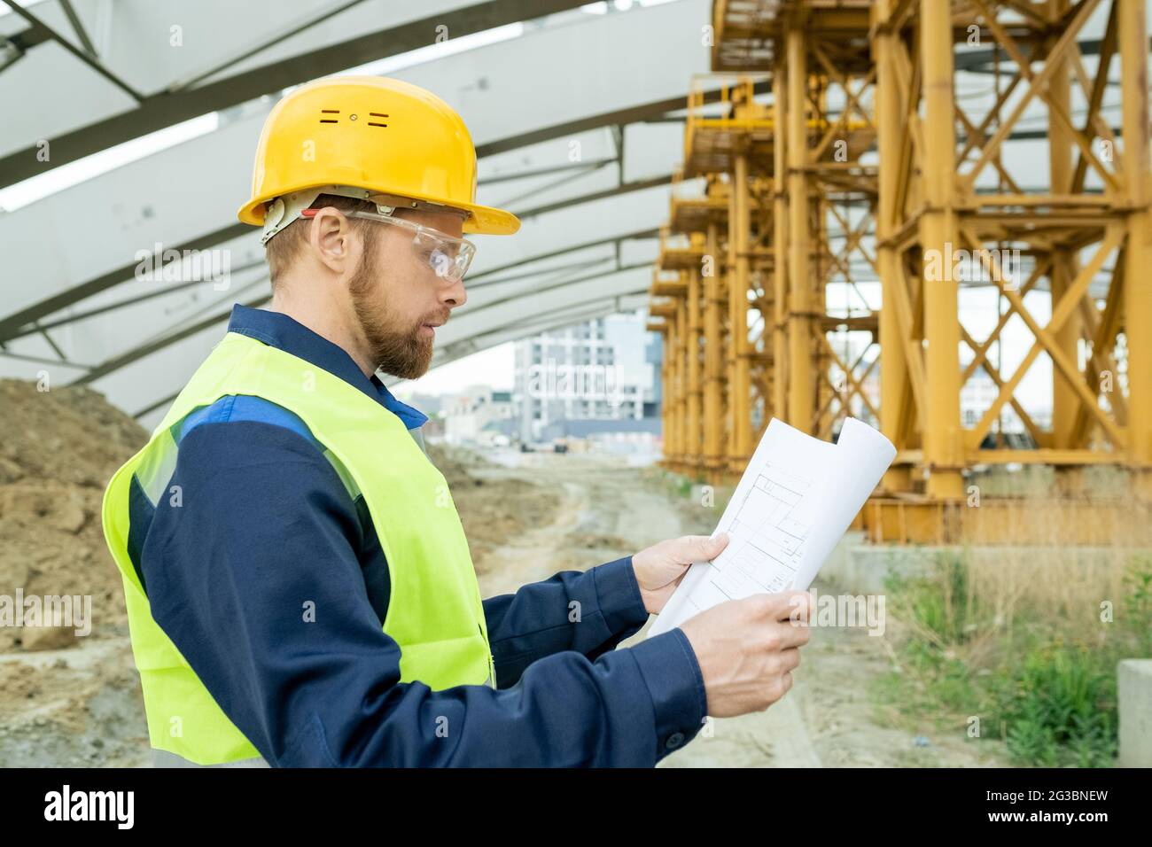 Side view of contemporary engineer holding blueprint with sketch of ...