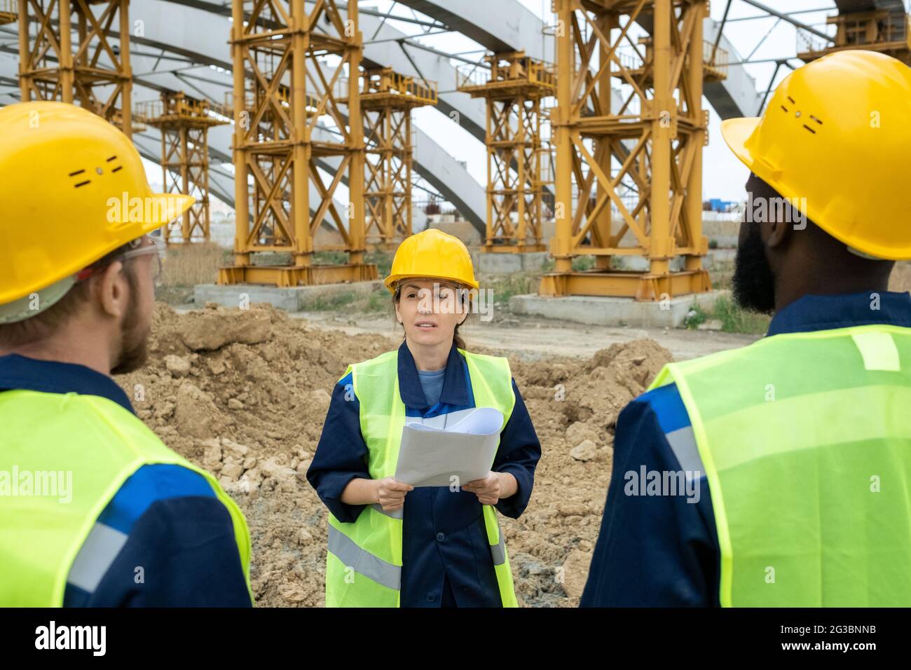Female engineer in workear talking to her male colleagues at meeting ...