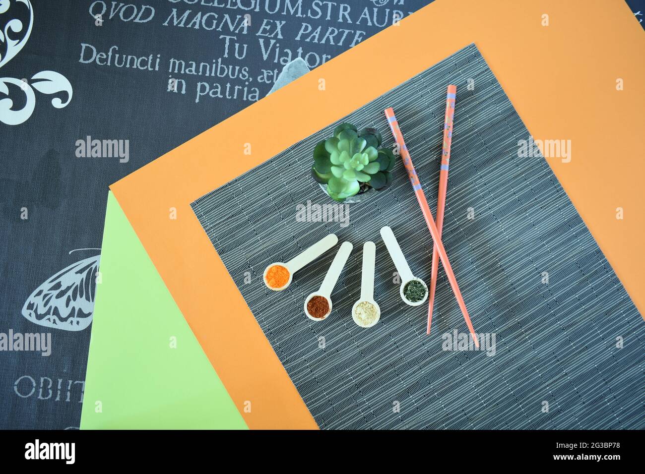 Closeup shot of spices on white spoons and a houseplant with chopsticks ...