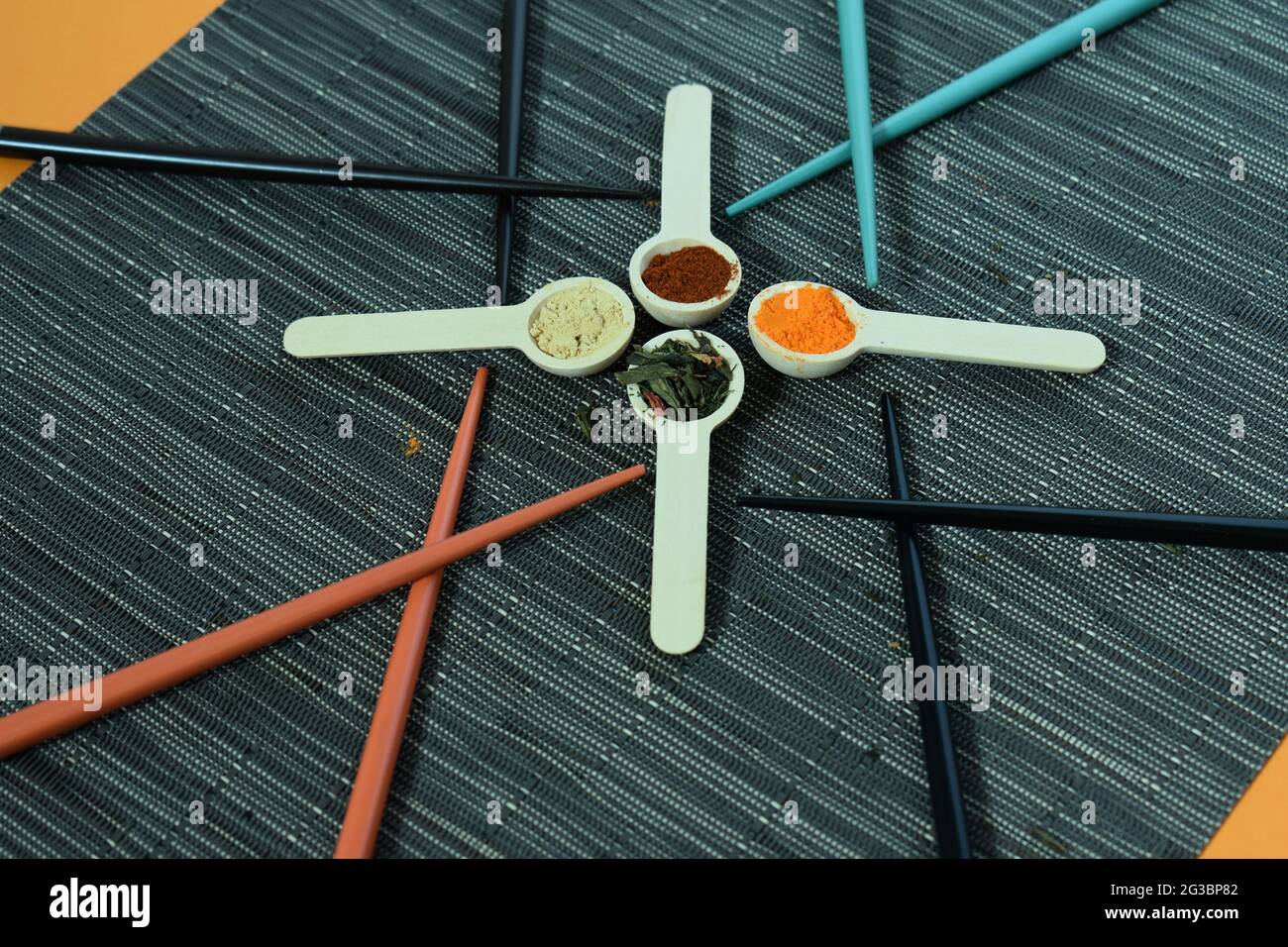 Closeup shot of spices on white spoons and chopsticks on a black ...