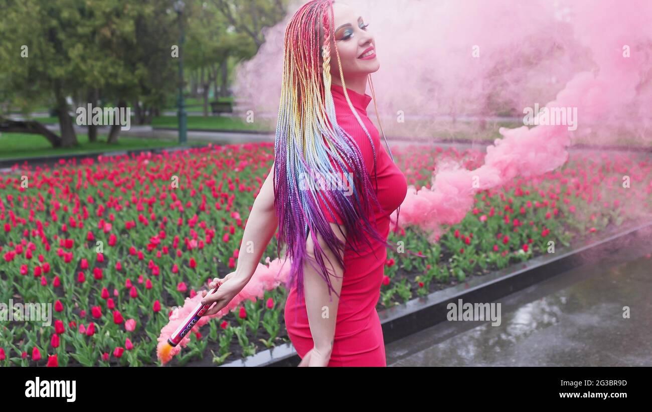 An extraordinary girl in a red dress with makeup and colored braids ...