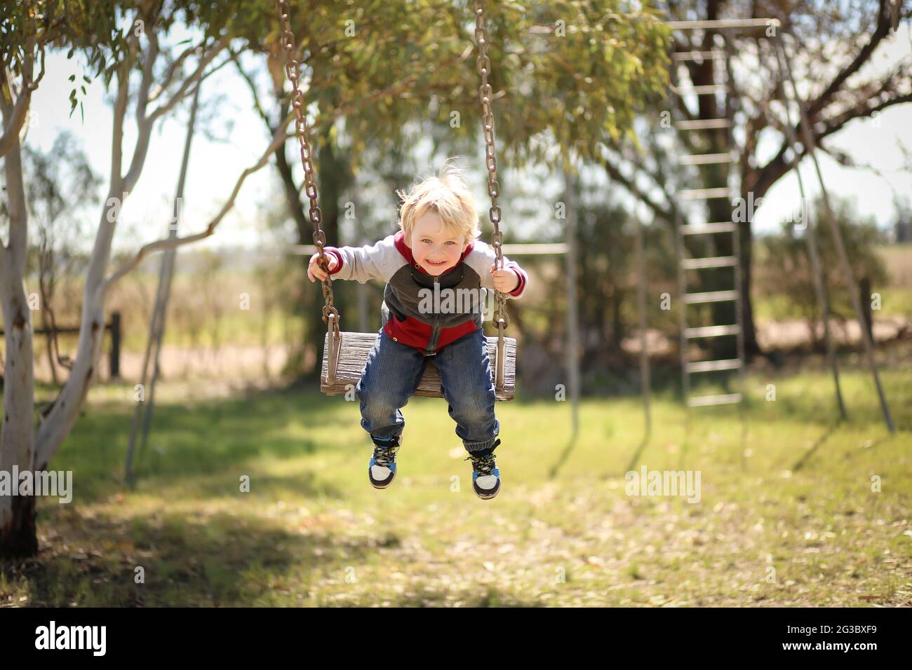 Happy adorable blonde Australian kid swinging in the playground Stock ...