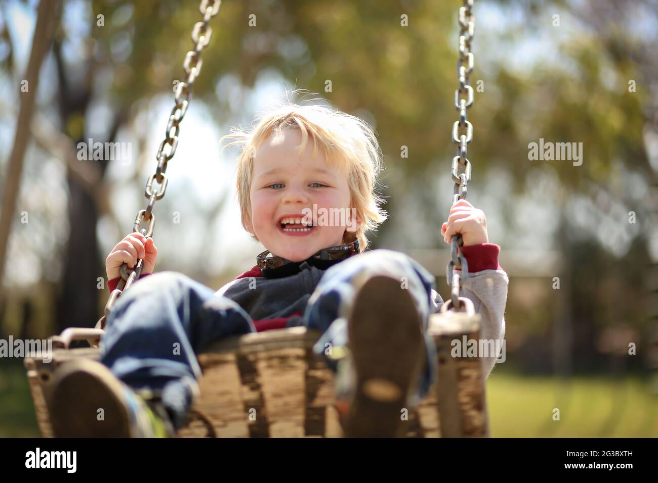 Happy adorable blonde Australian kid swinging in the playground Stock ...