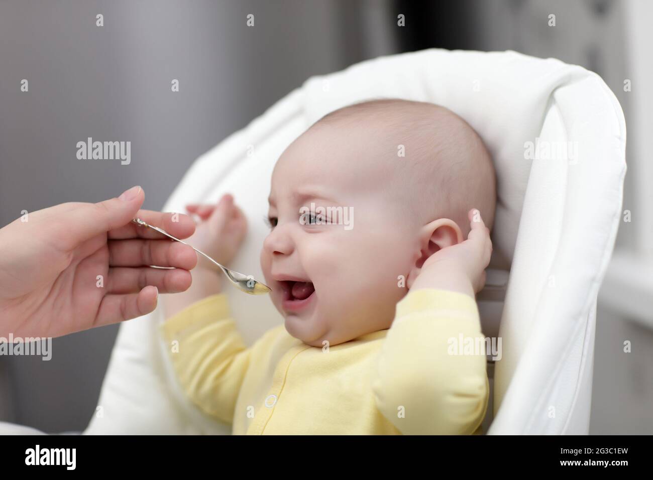 The crying baby with spoon food at home Stock Photo - Alamy