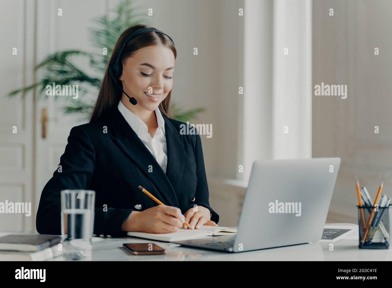 Smiling young businesswoman looking down and writing notes Stock Photo ...