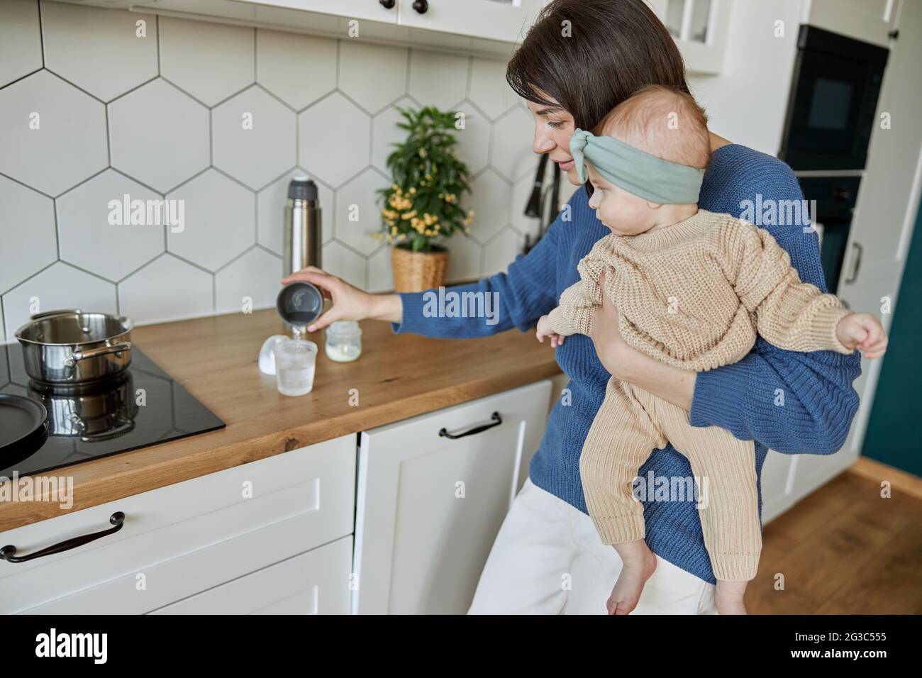 Mother pouring water into bottle to prepare milk Stock Photo - Alamy