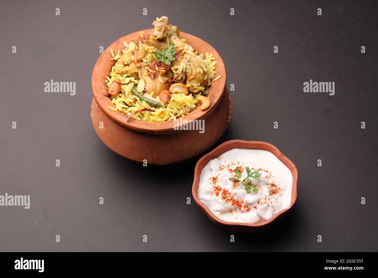 Spicy chicken dum biryani in traditional handi or clay pot. served with ...