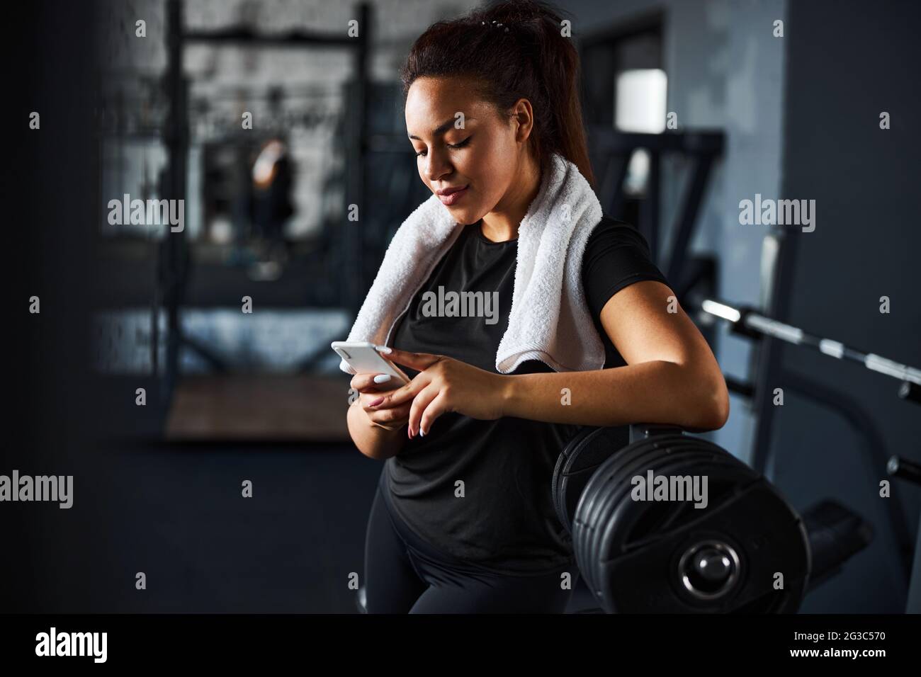 Happy young woman using mobile phone in gym Stock Photo - Alamy