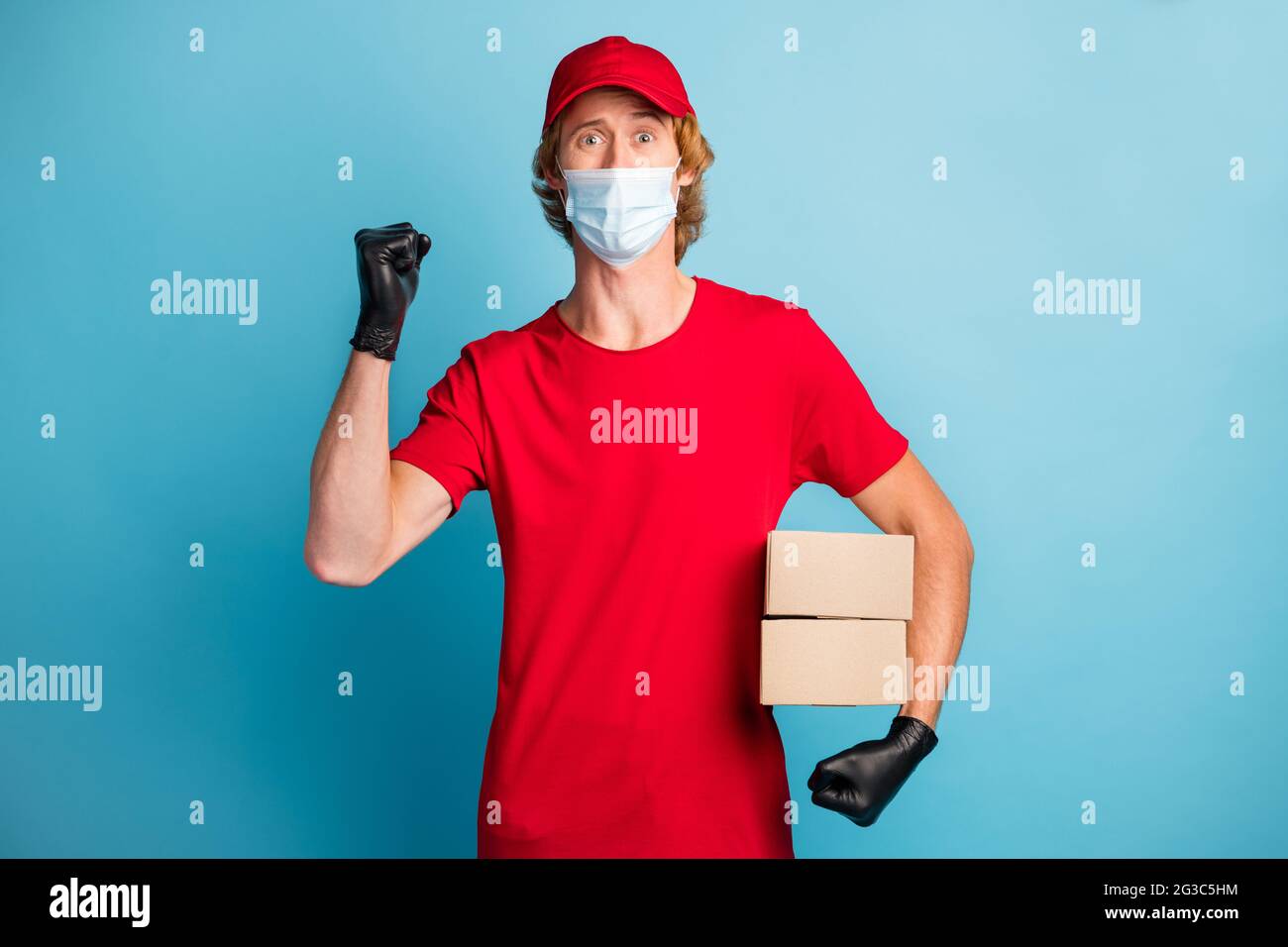 Photo of strong postman hold carton boxes fist up wear medical ...