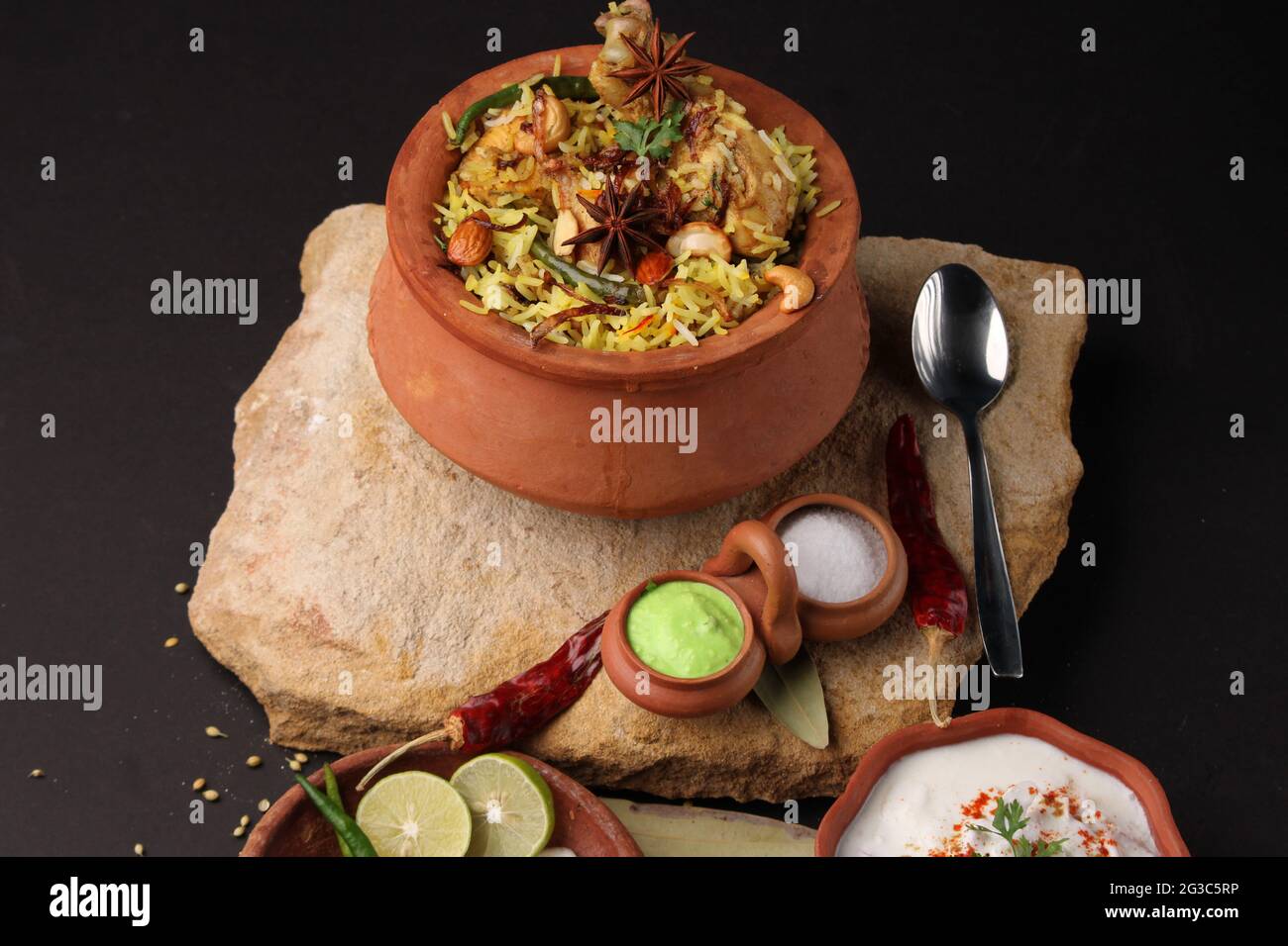 Spicy chicken dum biryani in traditional handi or clay pot. served with ...