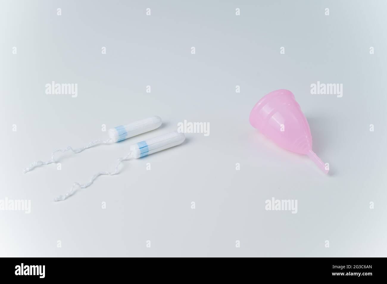 Pink menstrual cup and tampons on a white background. Comparison of ...