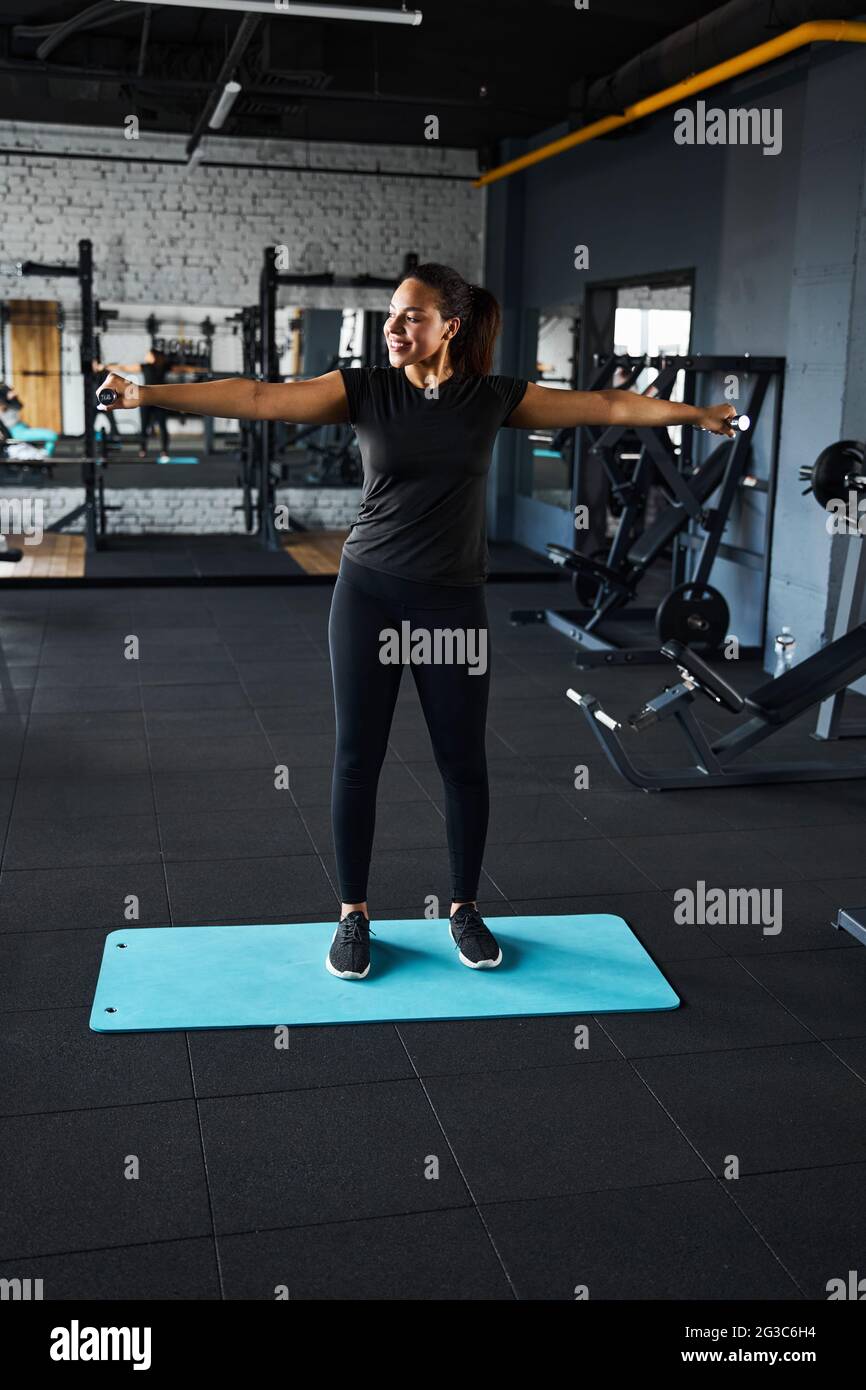 Jolly young woman training shoulders in gym Stock Photo - Alamy