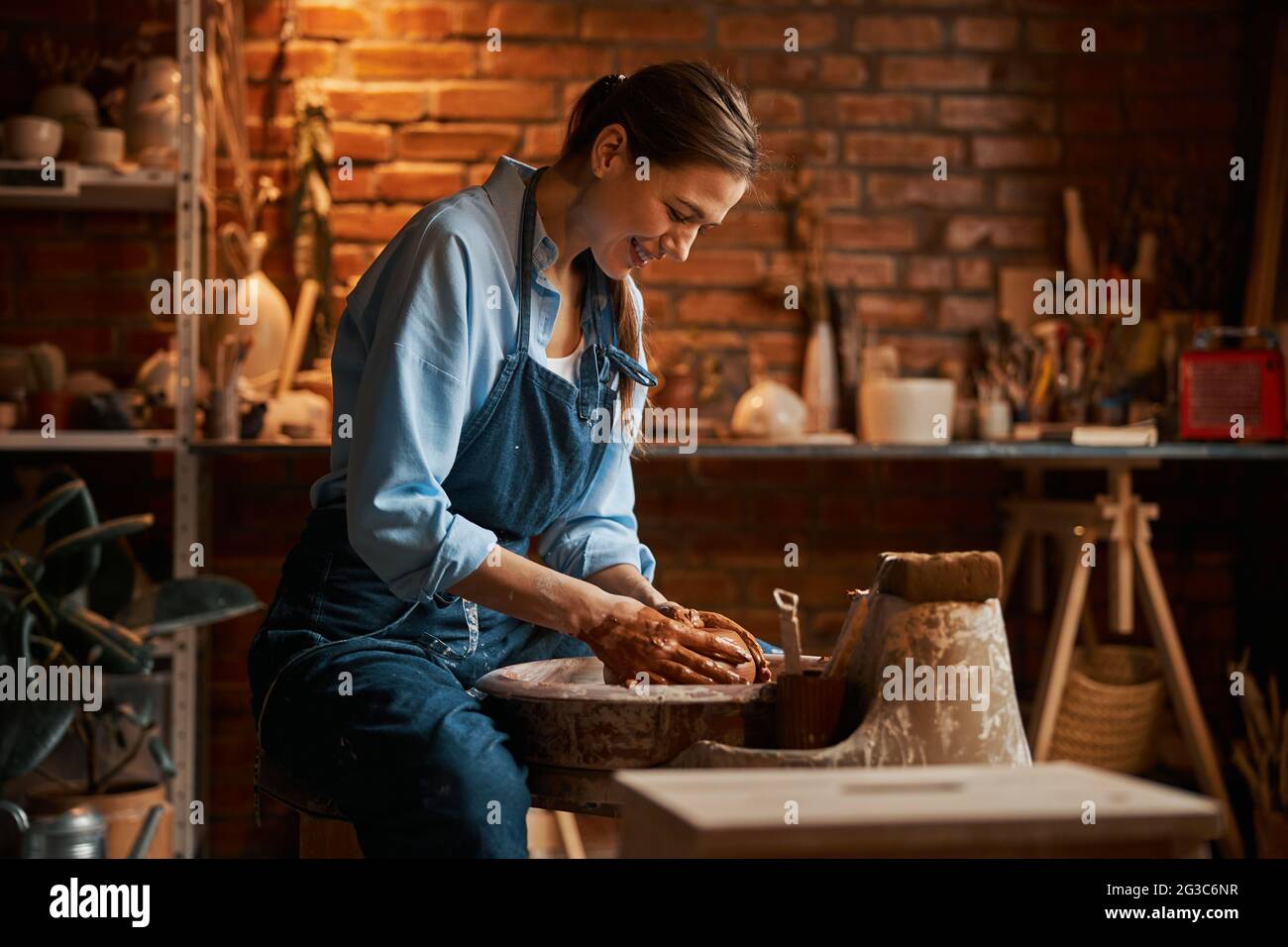 Professional ceramicist shaping clay pot in pottery workshop while ...