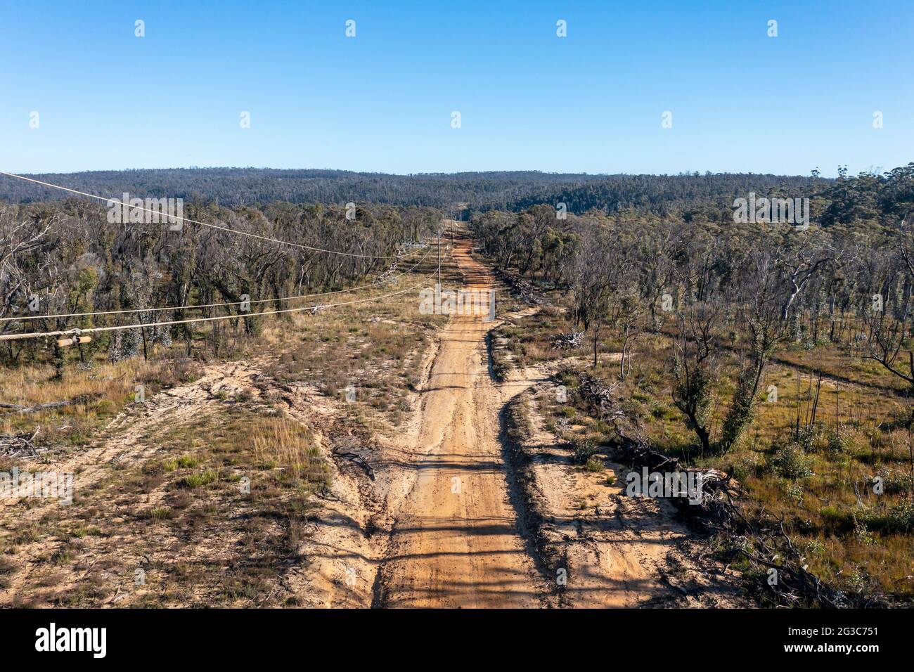 Drone aerial photograph of telephone poles and wires along a dirt track ...