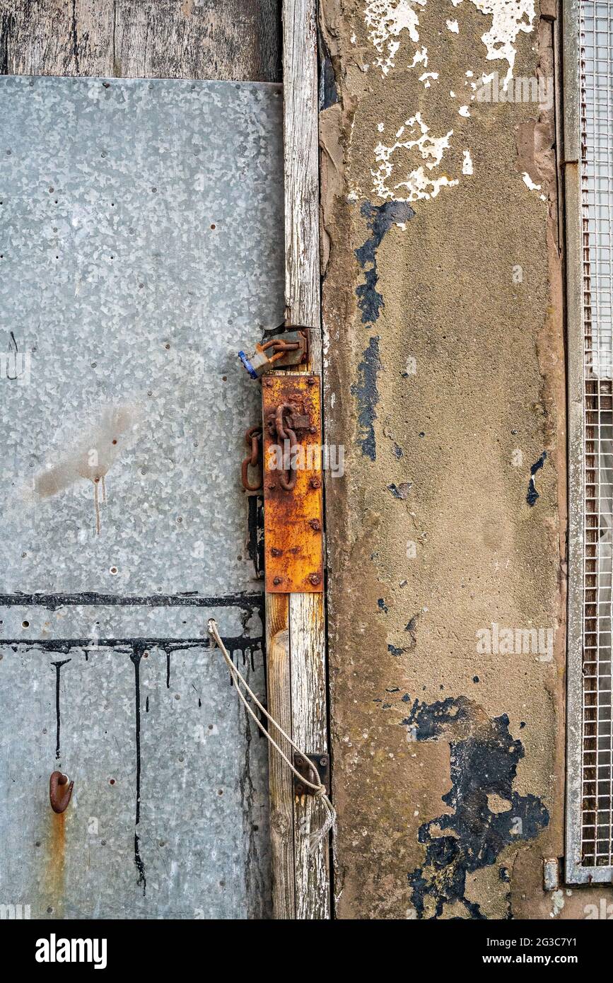 Rusty door furniture on run-down wood and metal exterior street door of ...