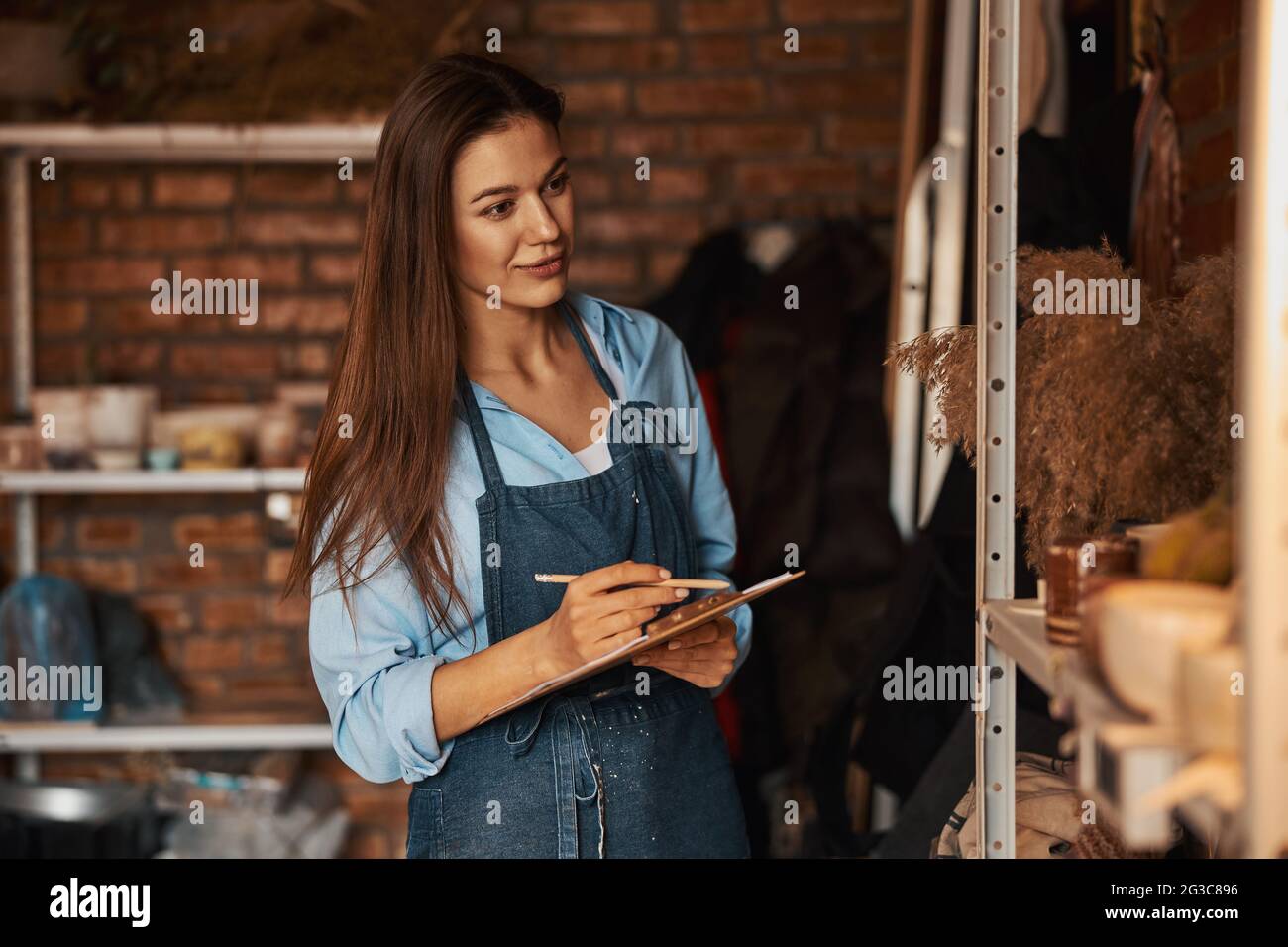 Beautiful elegant craft woman with long hair holding clipboard in hands ...