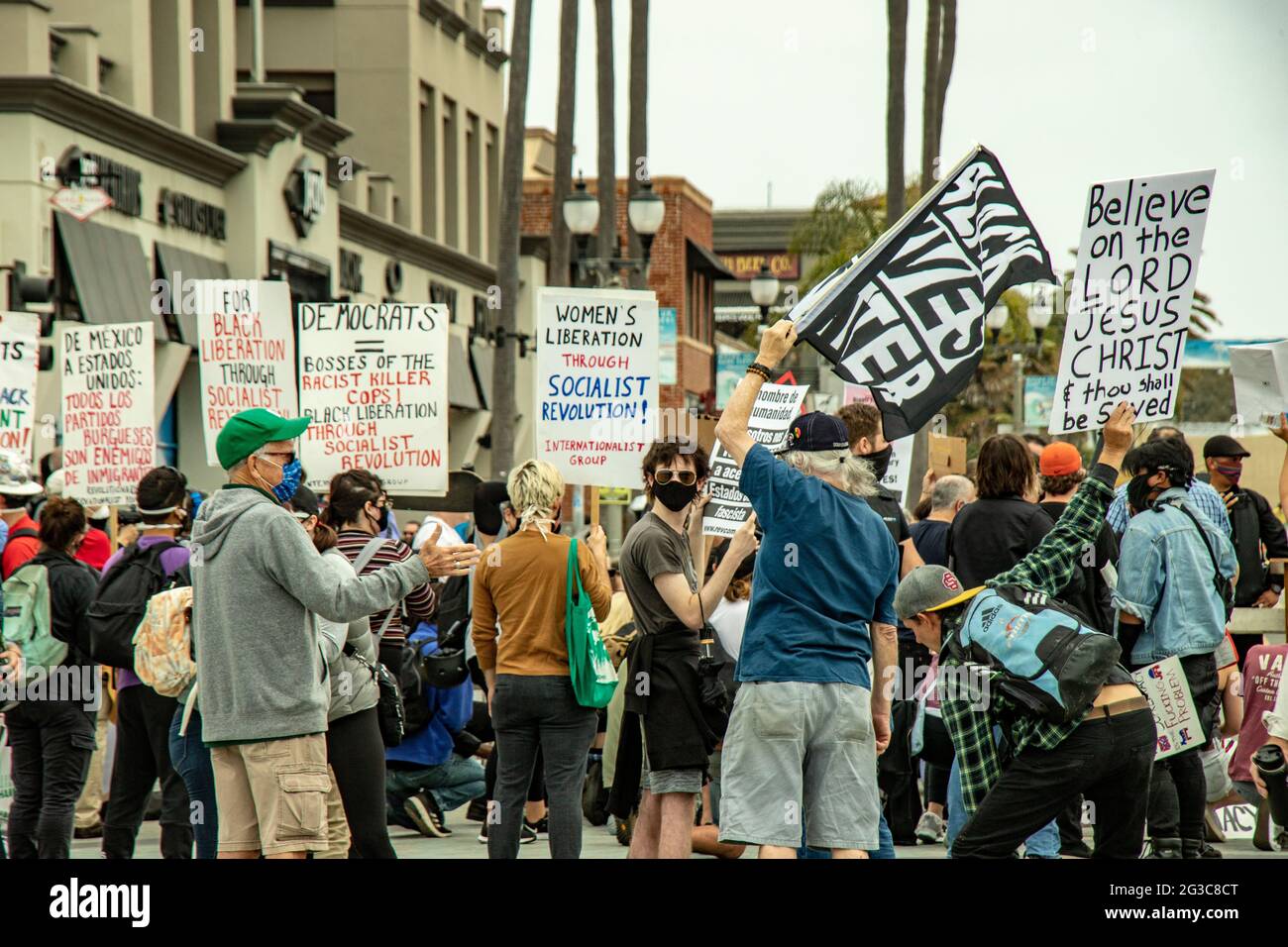 Demonstrators in Huntington Beach, CA, carry signs protesting ...