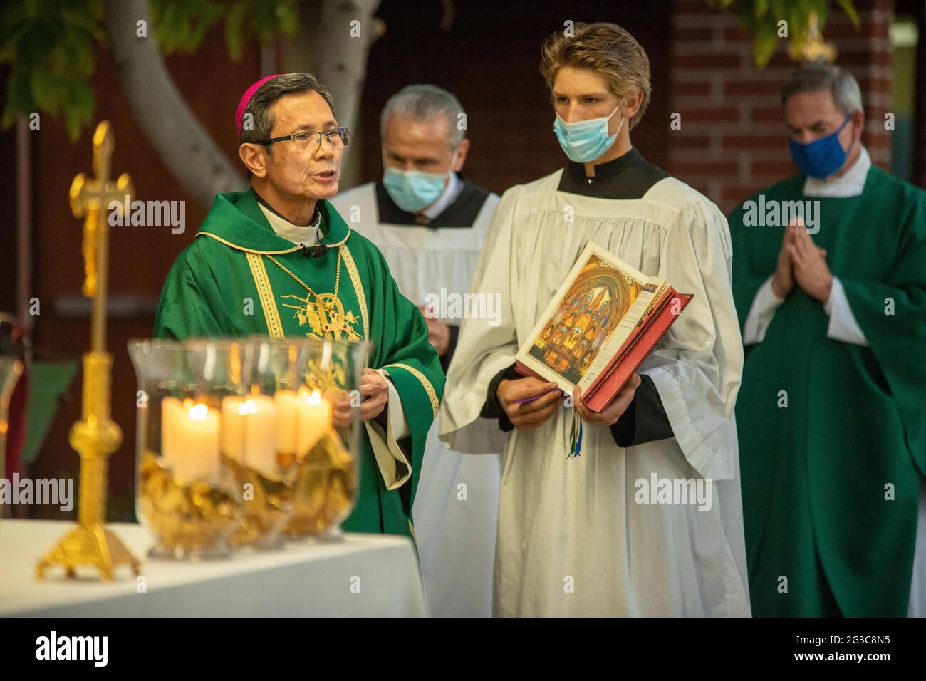 An Asian American priest reads from a Bible at a mass for recognition ...