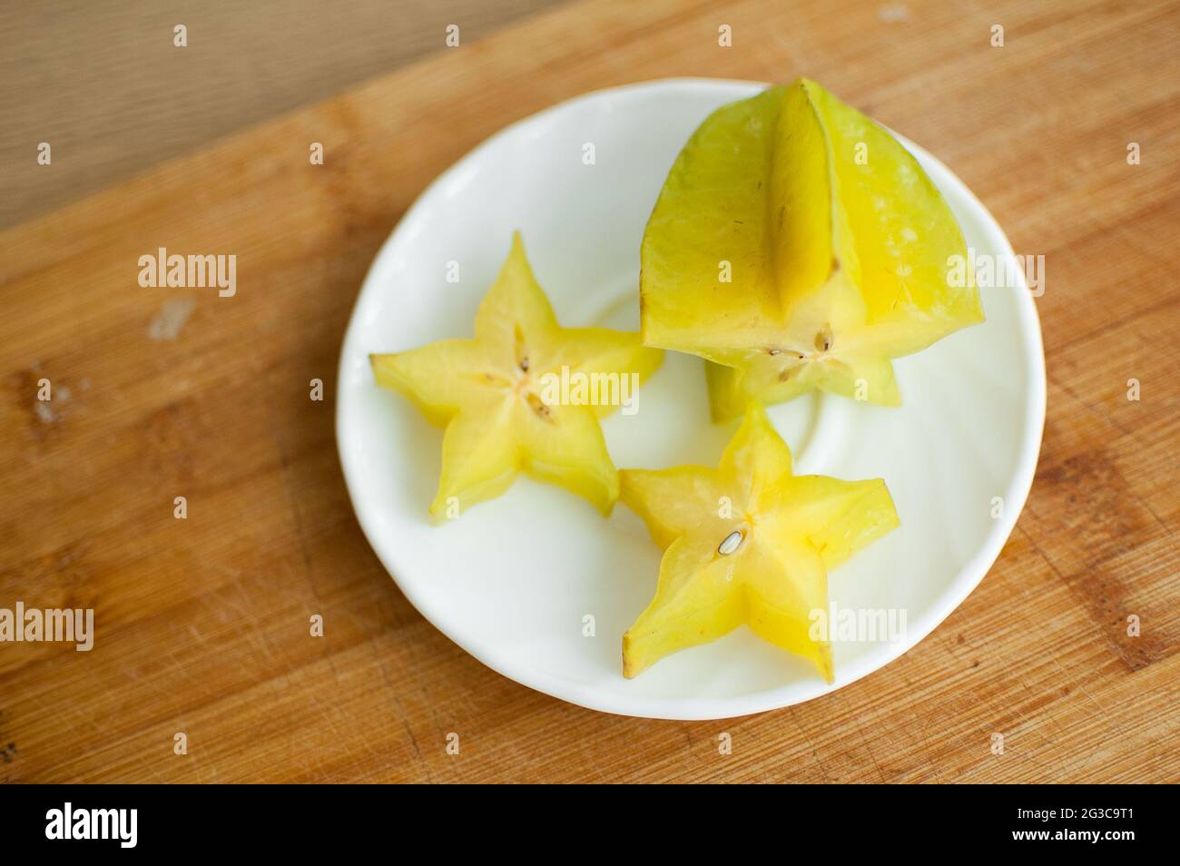 Exotic starfruit or averrhoa carambola on white plate on wooden cut ...