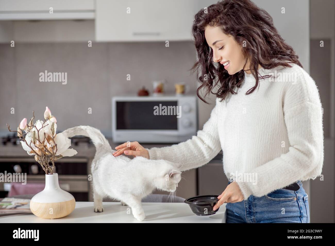 Cute young woman stroking her white cat Stock Photo - Alamy