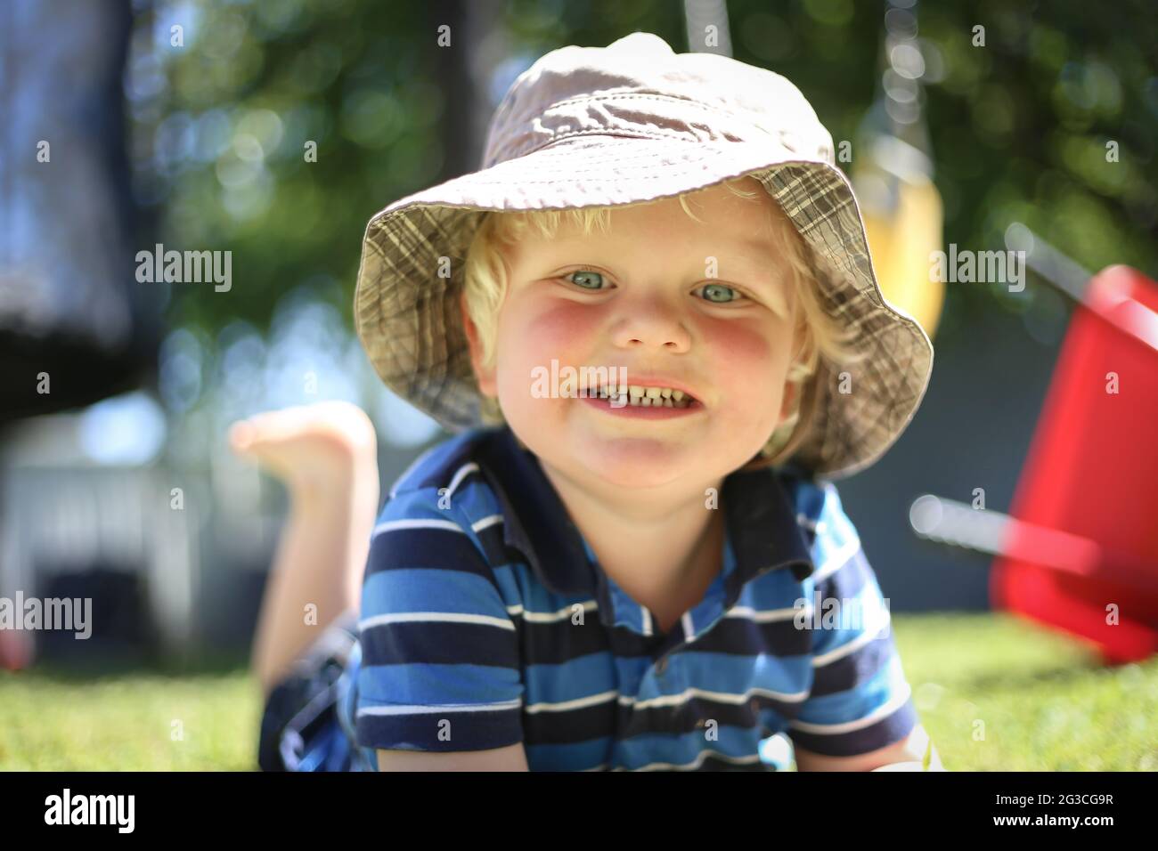 Happy adorable blonde Australian kid lying on the grass in the ...