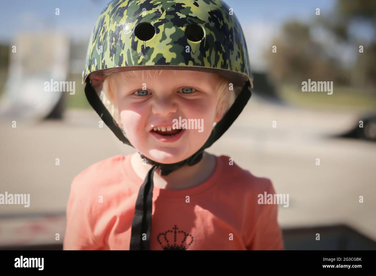Cute and adorable blonde Australian kid with a helmet in the playground ...
