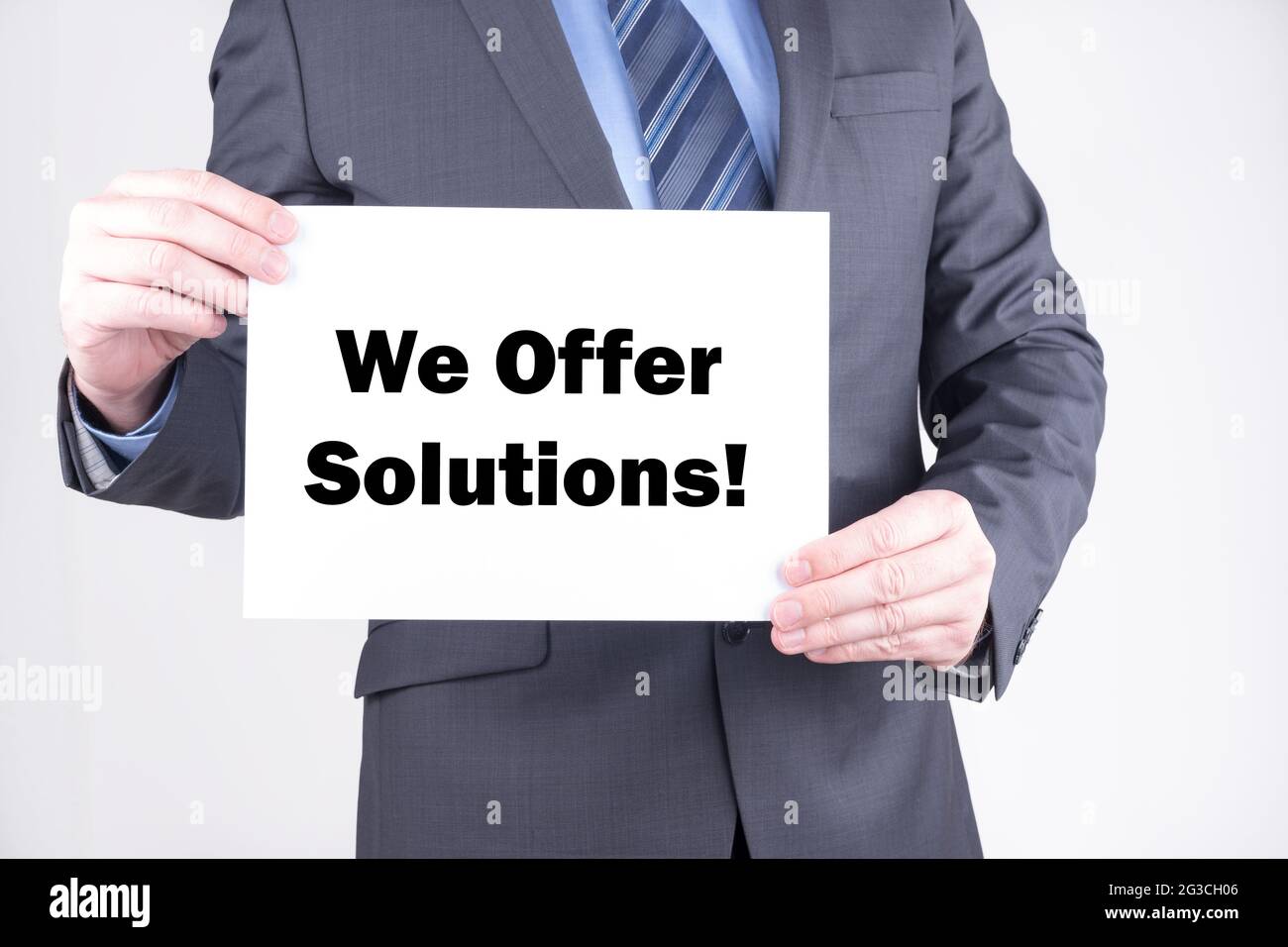 Man in a suit showing a paper sign with the text "we offer solutions ...