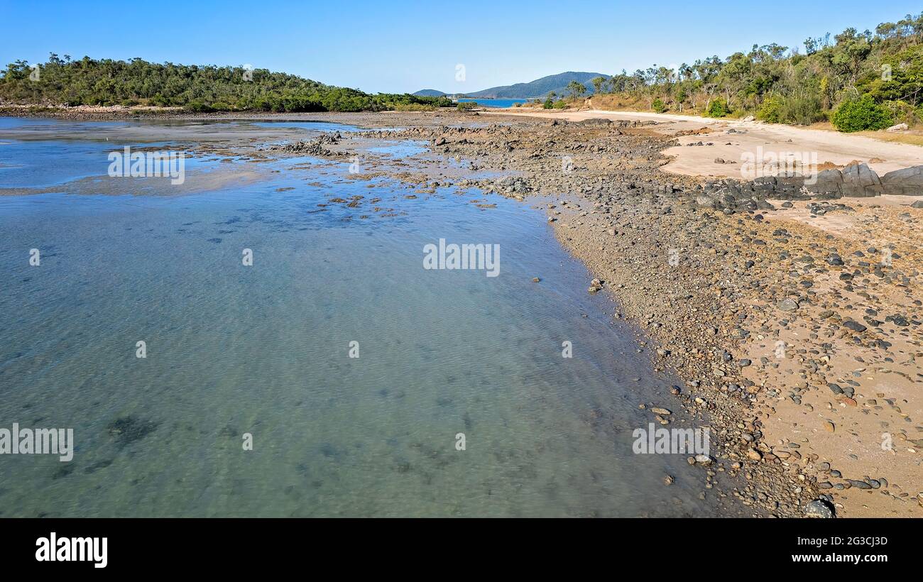 Aerial view of a muddy seabed with a rocky coastal shoreline at low ...