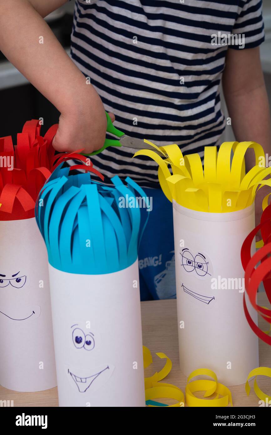 Preschool boy cutting paper hair with scissors on handmade funny heads ...