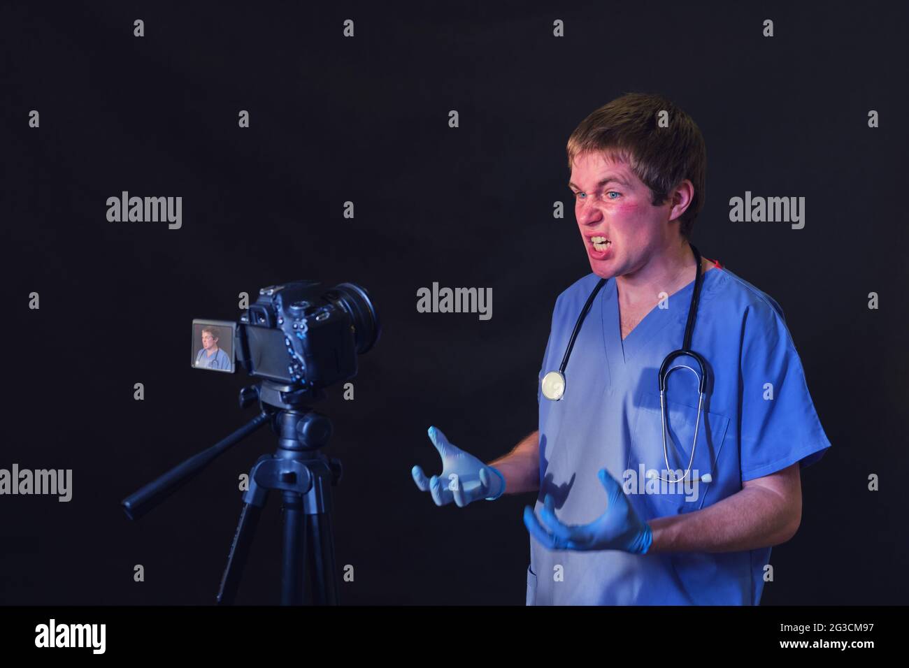 Angry medic yells at video camera on black background, problems doctors ...