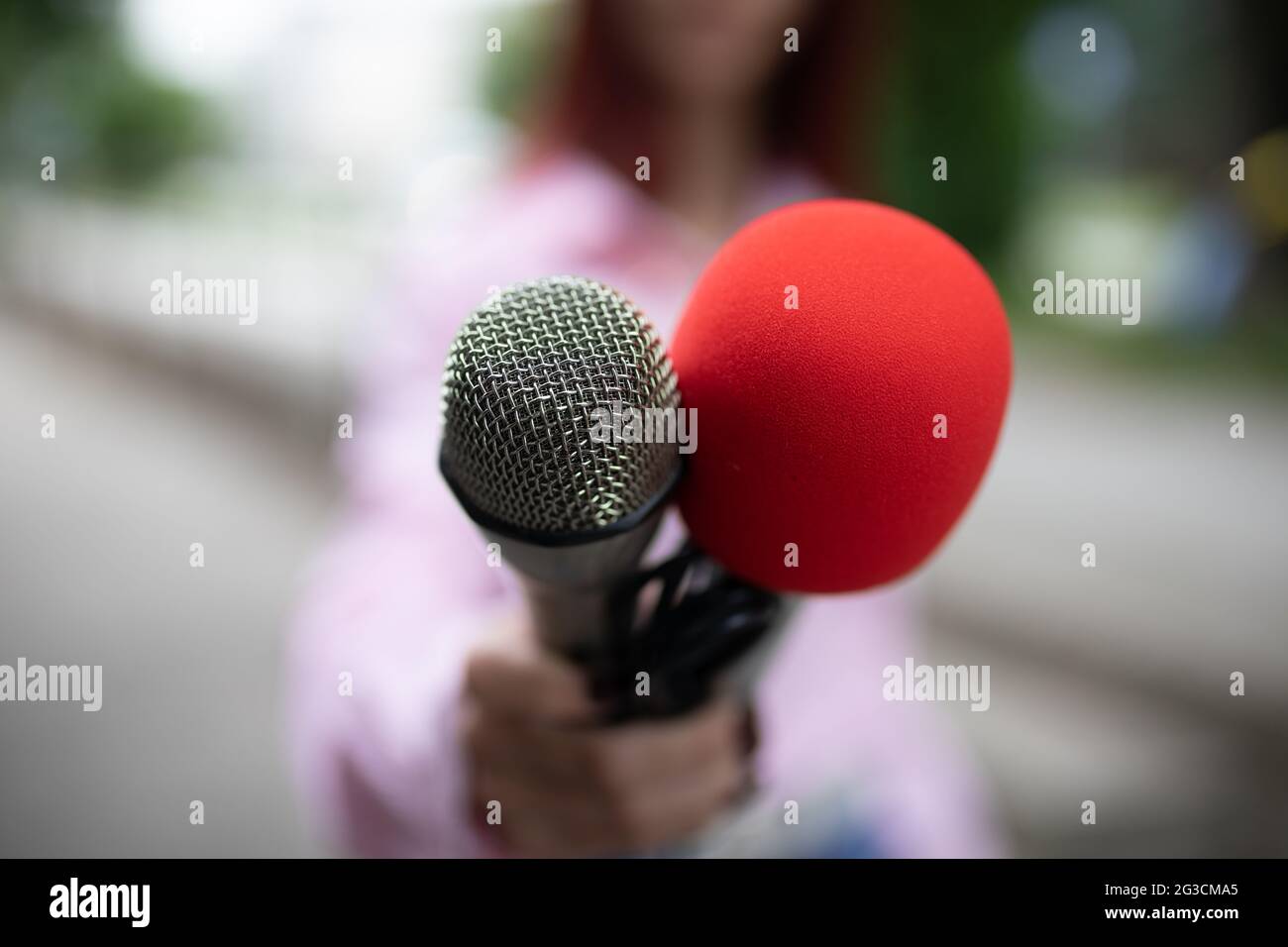 Professional female journalist in action, holding microphones and ...