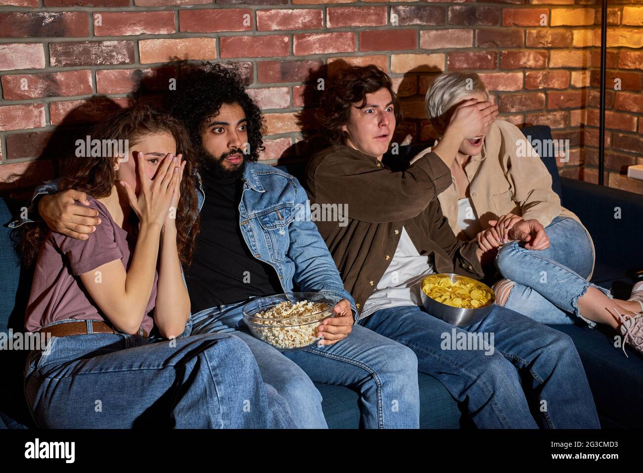 Group of friends watching scary movie at home, eating popcorn, sitting ...