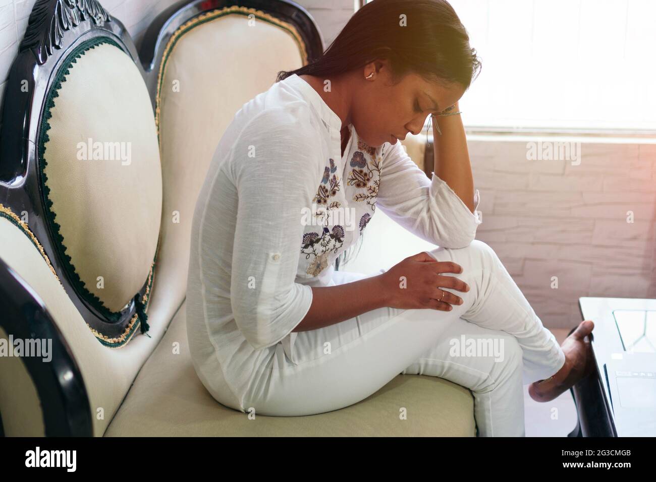 Black woman crying while sitting on an armchair in the living room of ...