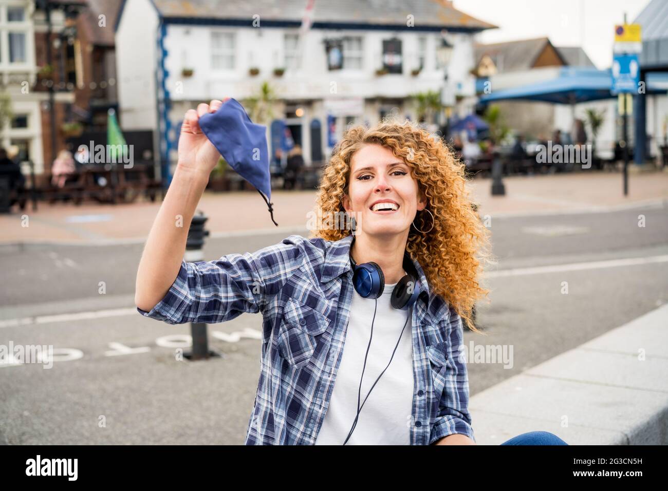 Young happy caucasian woman takes off a protective face-covering mask ...