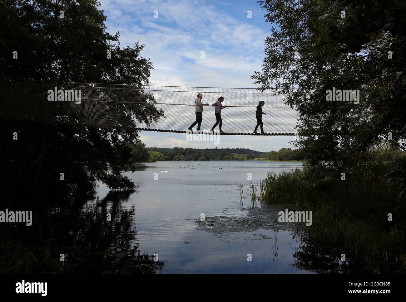 A family tentatively cross the rope bridge in the playground area with ...