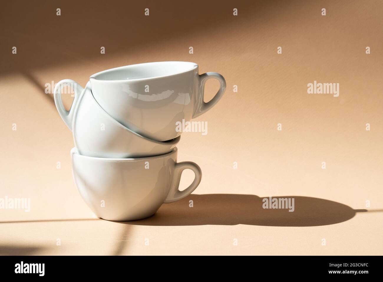 Three ceramic cups on beige studio background Stock Photo - Alamy