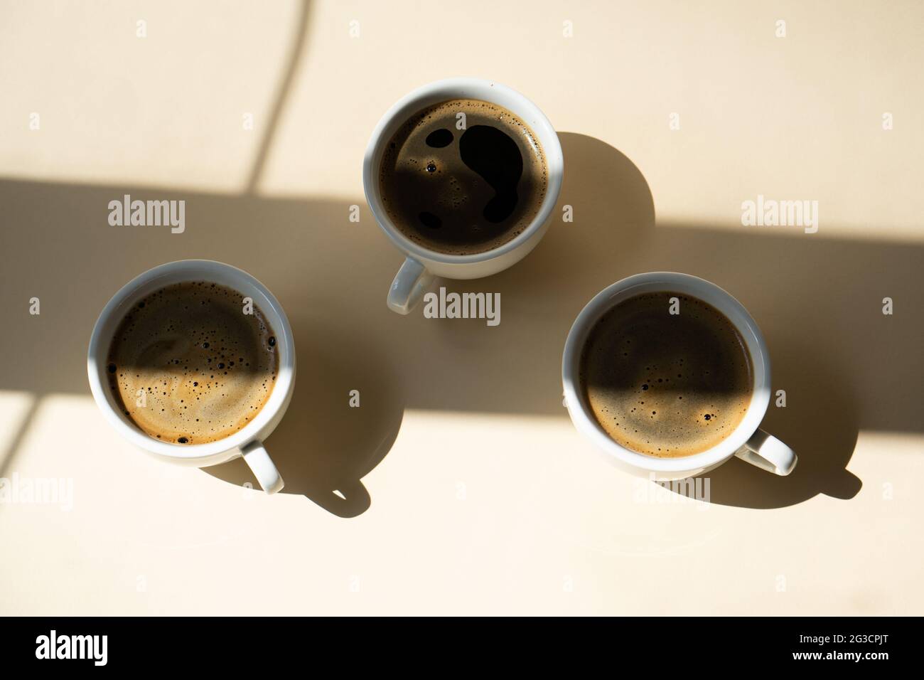Three cups of coffee on beige studio background Stock Photo - Alamy