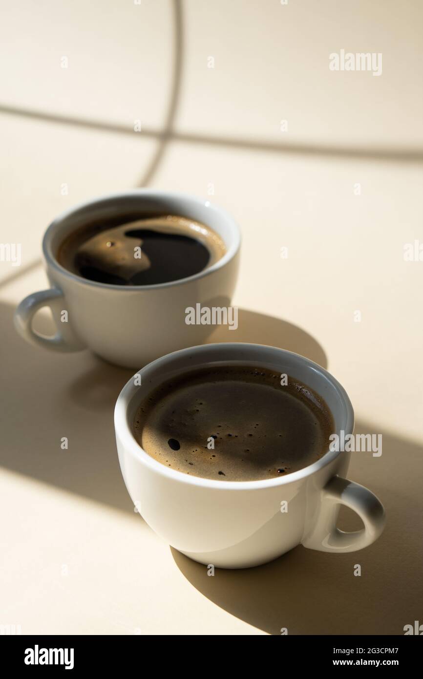 Two cups of coffee on beige studio background Stock Photo - Alamy