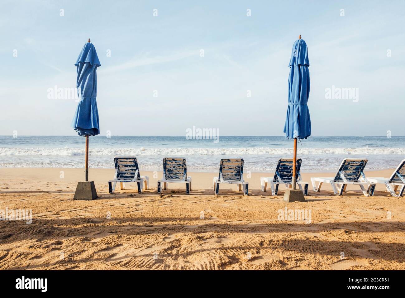 sun chairs with blue umbrella on empty beach Stock Photo - Alamy