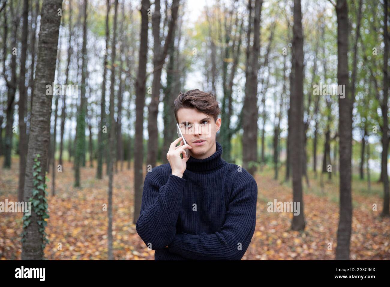 A man in a forest during autumn makes a phone call, all the leaves on ...