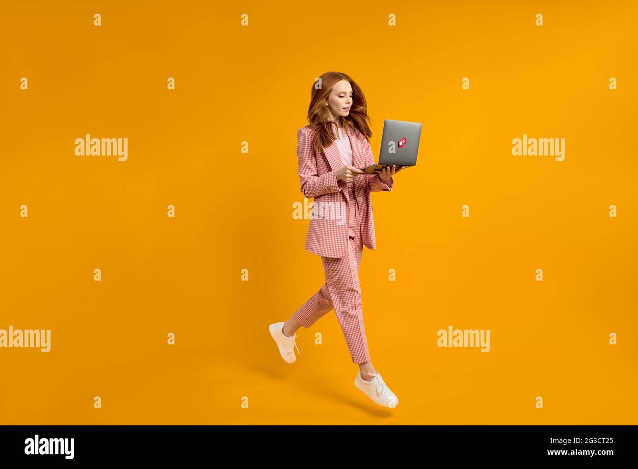 Happy jumping woman with laptop isolated on yellow studio background ...