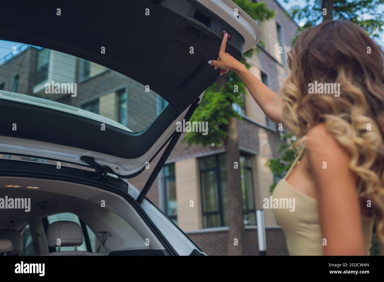 A young woman is opening the trunk of a car Stock Photo - Alamy
