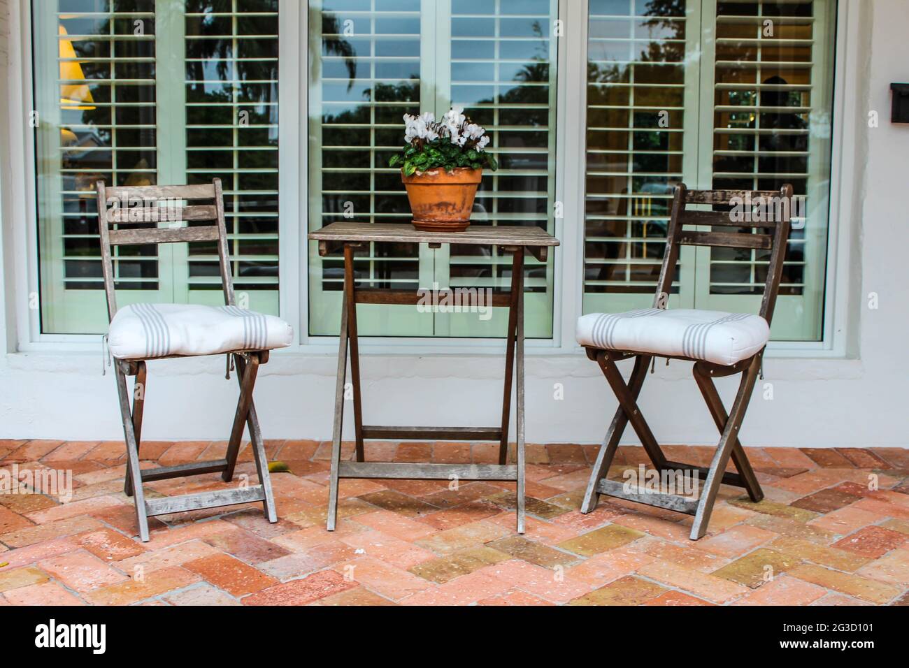 Wooden chairs and table outside a house, front porch area. Summer style ...