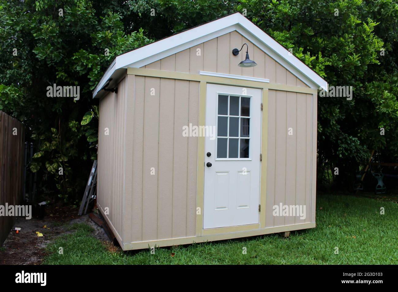 Side view of a backyard tool shed with a dog outside in a yard. Many ...